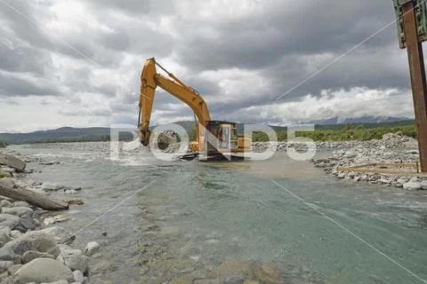 Photograph: 10 ton digger shifting shingle to deepen the channel in a ...