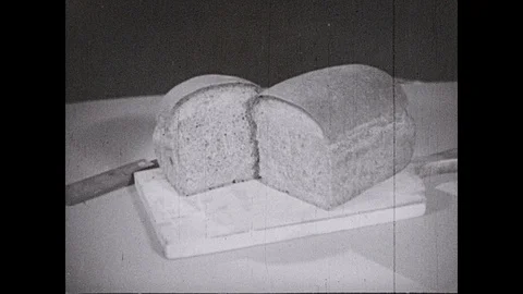 1930s: Loaf of bread cut in half on cutt... | Stock Video | Pond5