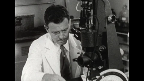 1940s: Man sits at microscope, swaps out... | Stock Video | Pond5