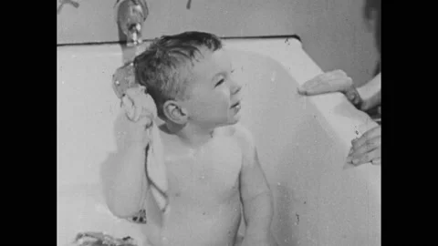 1950s: Baby taking bath. Woman with baby... | Stock Video | Pond5