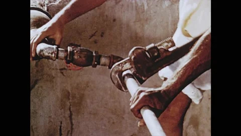 1950s: People tighten pipe with wrench. ... | Stock Video | Pond5
