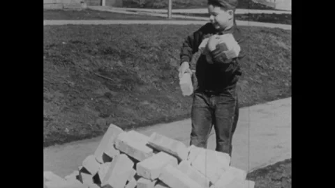 1950s: Young boy gathers bricks from pil... | Stock Video | Pond5
