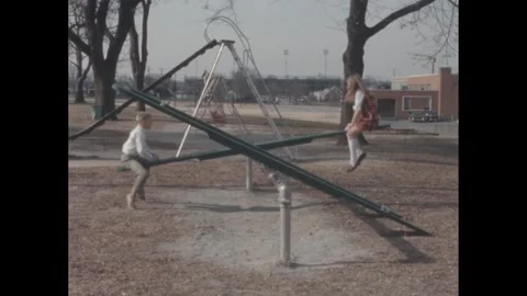 1960s: Boy and girl ride see-saw in sch... | Stock Video | Pond5