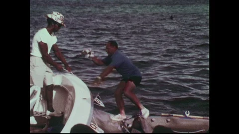 1960s: Dinghy captain hands six-pack of ... | Stock Video | Pond5