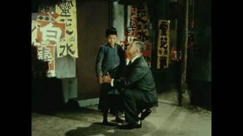 1960s: Man helps boy on ground get up. B... | Stock Video | Pond5