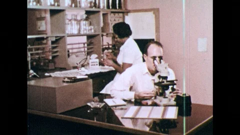 1960s: Woman works in lab. Man looks in... | Stock Video | Pond5