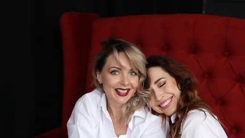 2 happy models posing on red sofa | Stock Video | Pond5