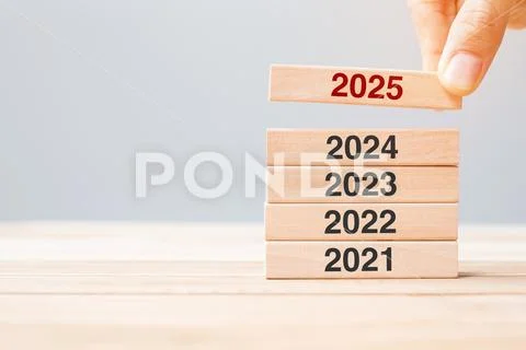 2025 block over 2024 and 2023 wooden building on table background ...