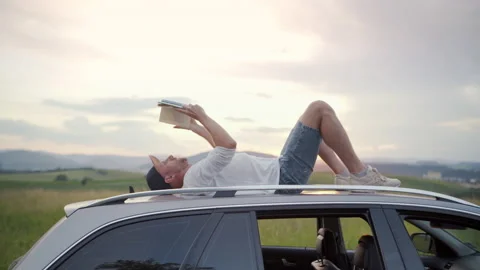 4K Driver lying down on his car's roof r... | Stock Video | Pond5