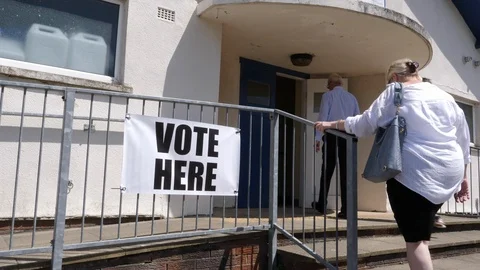 4K: Vote here Sign - People walking past... | Stock Video | Pond5