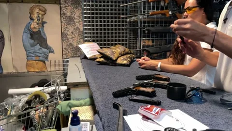 4k A woman learns how to load the gun at... | Stock Video | Pond5