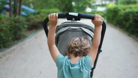 Adorable child helping to push stroller ... | Stock Video | Pond5