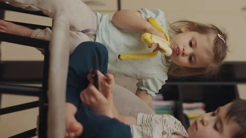 Adorable little girl eating banana looki... | Stock Video | Pond5