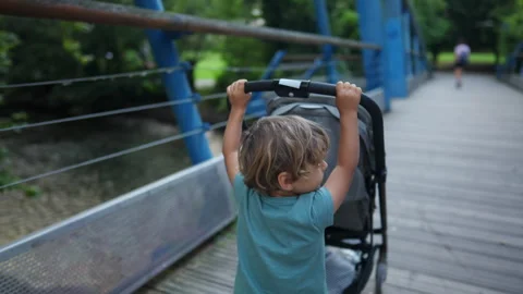 Adorable small boy helping to push strol... | Stock Video | Pond5