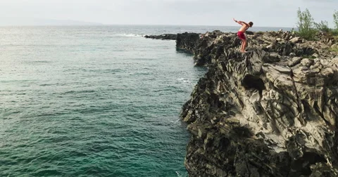 Aerial view cliff jumping into ocean | Stock Video | Pond5