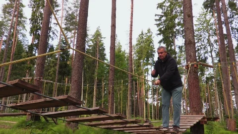 Afraid man walking on rope bridge in par... | Stock Video | Pond5