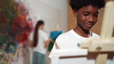 African boy painting canvas while girl d... | Stock Video | Pond5