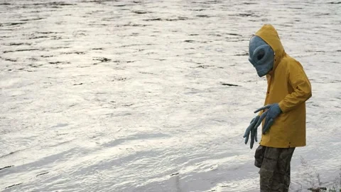 alien stands by river in yellow raincoat... | Stock Video | Pond5