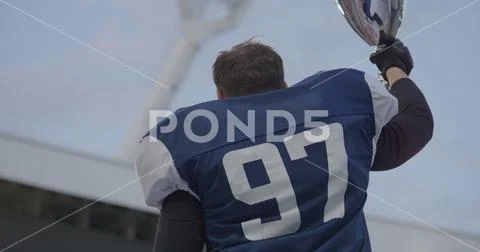American football player rising a trophy during a award ceremony on a ...