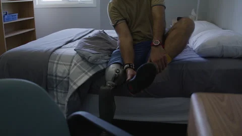 Amputee sitting on edge of bed | Stock Video | Pond5