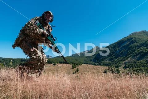 Photograph: Army soldier holding a sniper rifle with scope and walking ...