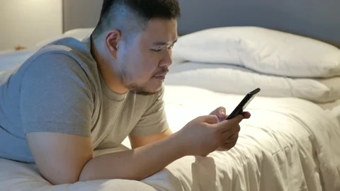 an asian man relaxing on the bed in bedr... | Stock Video | Pond5