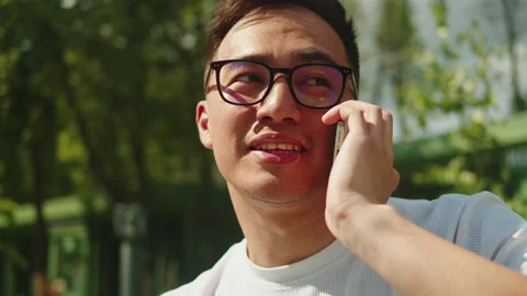 Asian man speaking on phone outdoor clos... | Stock Video | Pond5