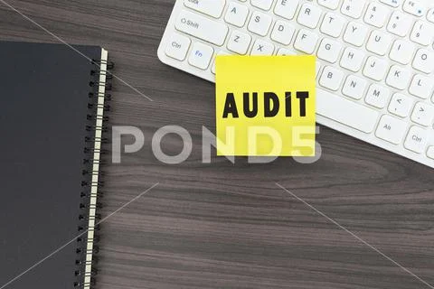 Audit word on adhesive note on top of white keyboard on wooden table ...