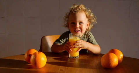 Baby boy joyfully sips orange juice from... | Stock Video | Pond5