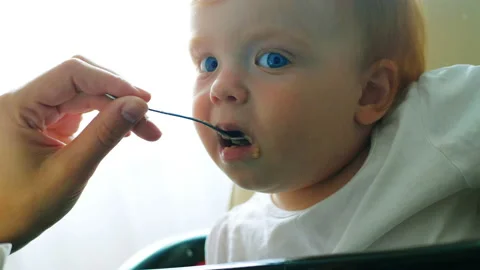 Baby eating puree with spoon. Close up o... | Stock Video | Pond5