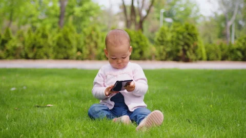 Baby girl concentrating on her phone at ... | Stock Video | Pond5