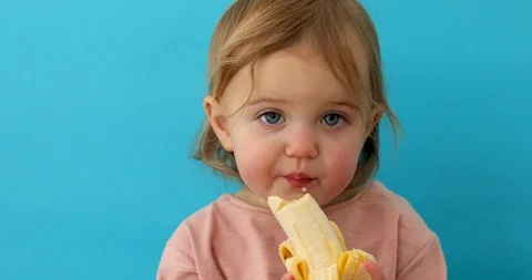 Baby girl eating banana | Stock Video | Pond5