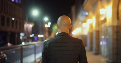 Back view bald man walking at night city | Stock Video | Pond5