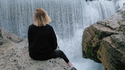 Back view. Blonde girl sitting on the ro... | Stock Video | Pond5
