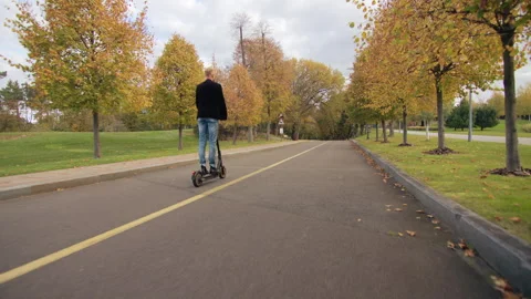 Back view of man on e-scooter driving sl... | Stock Video | Pond5