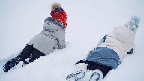 Back view of two kids crawling on snow o... | Stock Video | Pond5