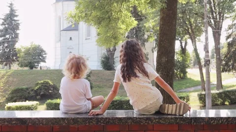 Back view of two sisters sitting in city... | Stock Video | Pond5