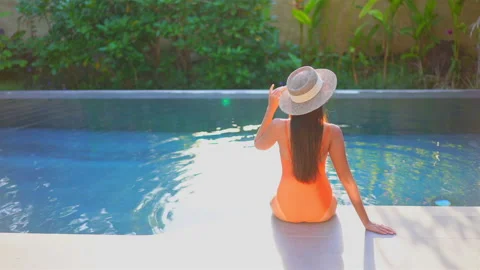 Back view of woman sitting on pool edge ... | Stock Video | Pond5