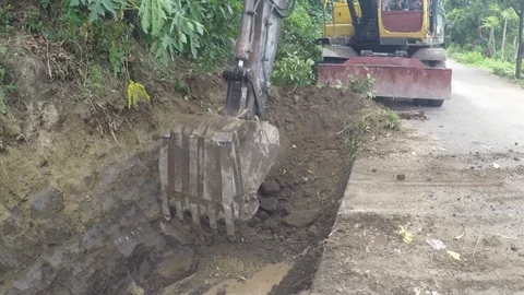 Backhoe digging pit at the side of road | Stock Video | Pond5