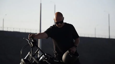 A bald biker with a motorcycle helmet si... | Stock Video | Pond5