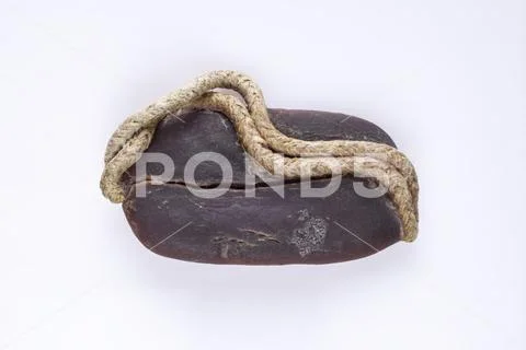 Photograph: Bar of old tar soap with string on white background #120646762