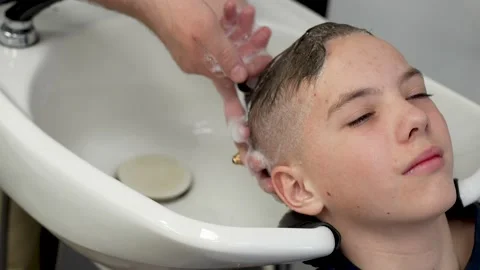 Barber washes the boy hair in wash basin | Stock Video | Pond5