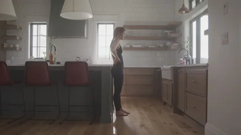 Barefoot Woman Stands in Kitchen | Stock Video | Pond5