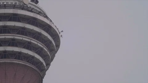 Base jumpers jumping from Menara tower i... | Stock Video | Pond5