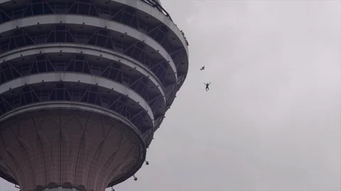 Base jumpers jumping from Menara tower i... | Stock Video | Pond5