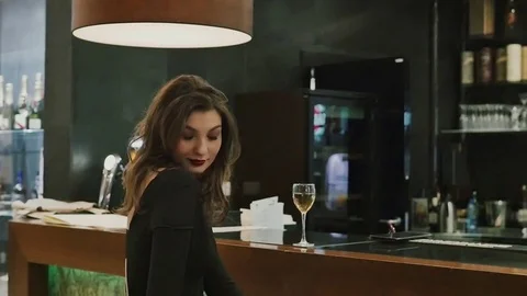 A beautiful girl is sitting at the bar c... | Stock Video | Pond5