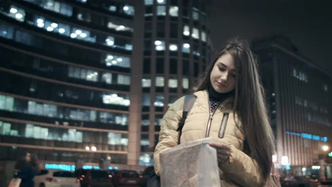 A beautiful girl is watching a map at ni... | Stock Video | Pond5