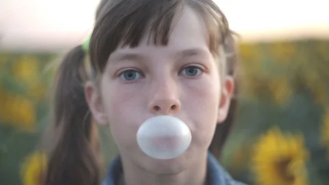 Beautiful teen girl inflating bubble of ... | Stock Video | Pond5