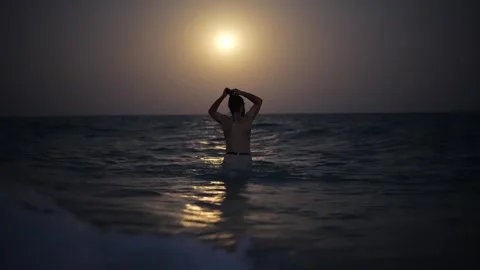 Beneath a full moon, a man wades into th... | Stock Video | Pond5