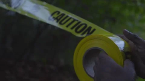 black man rolling up caution tape in woo... | Stock Video | Pond5